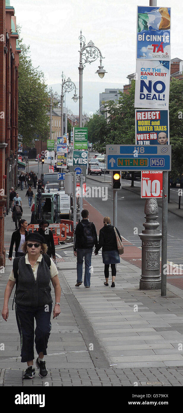 People walk past signs in support and against the European Fiscal ...