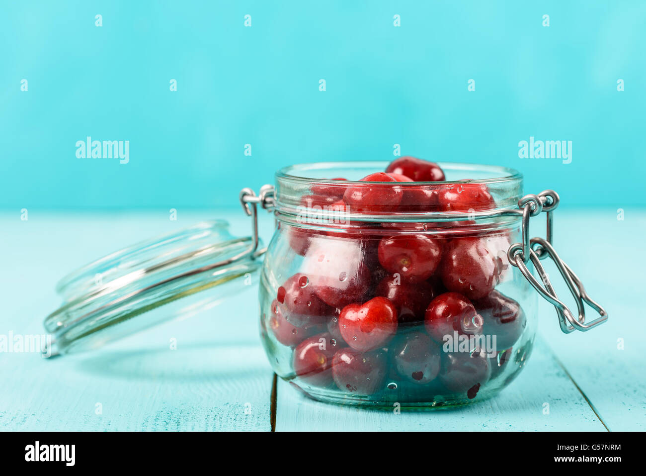 Jar Of Red Fresh Cherries On Turquoise Background Stock Photo - Alamy