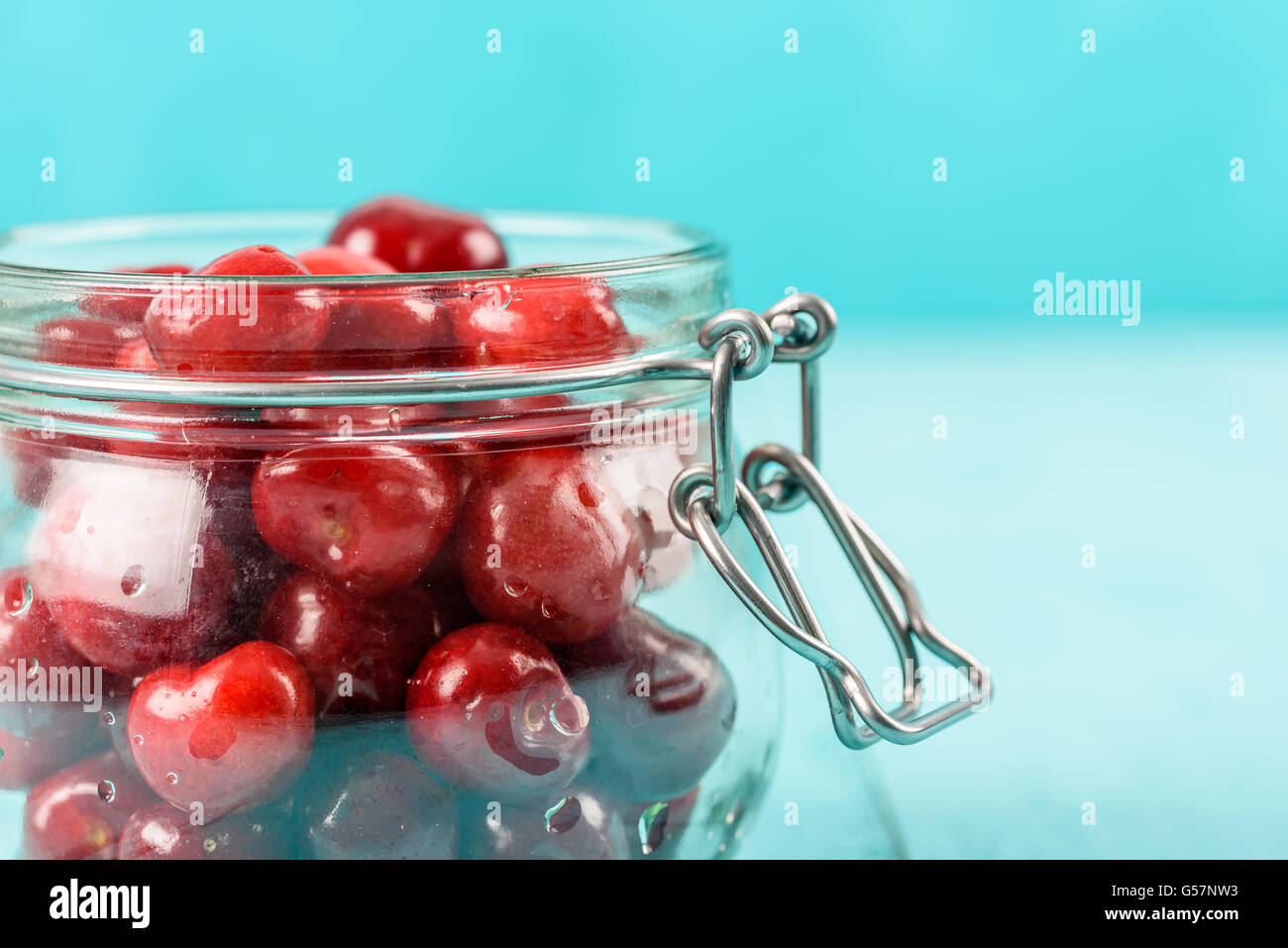 Jar Of Red Fresh Cherries On Turquoise Background Stock Photo - Alamy