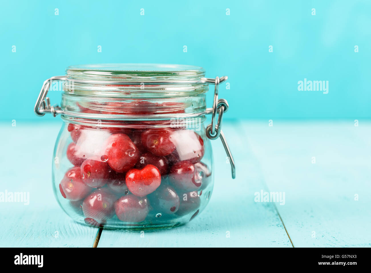 Jar Of Red Fresh Cherries On Turquoise Background Stock Photo - Alamy