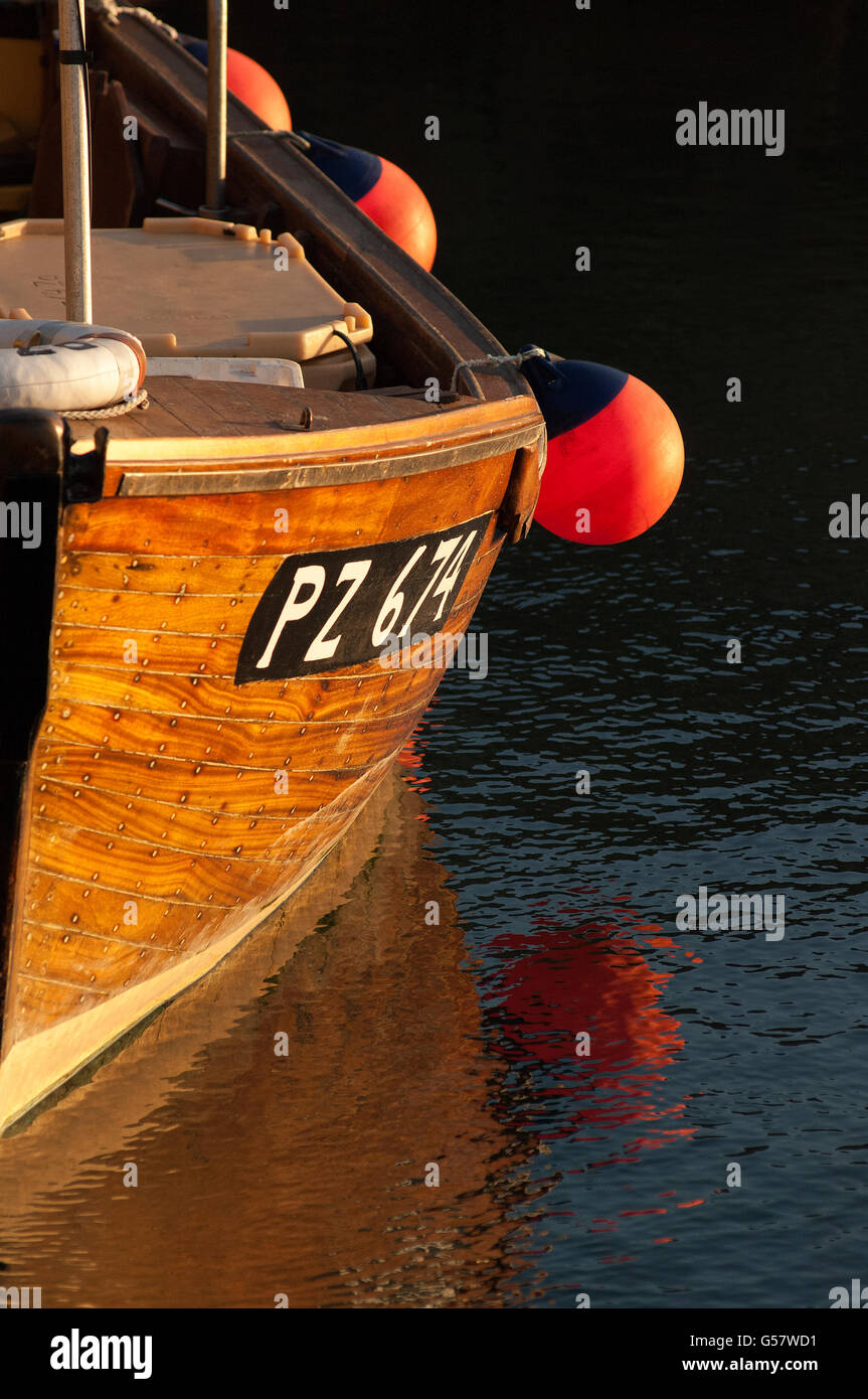 Hull of fishing boat with red fenders illuminated by warm sunlight ...