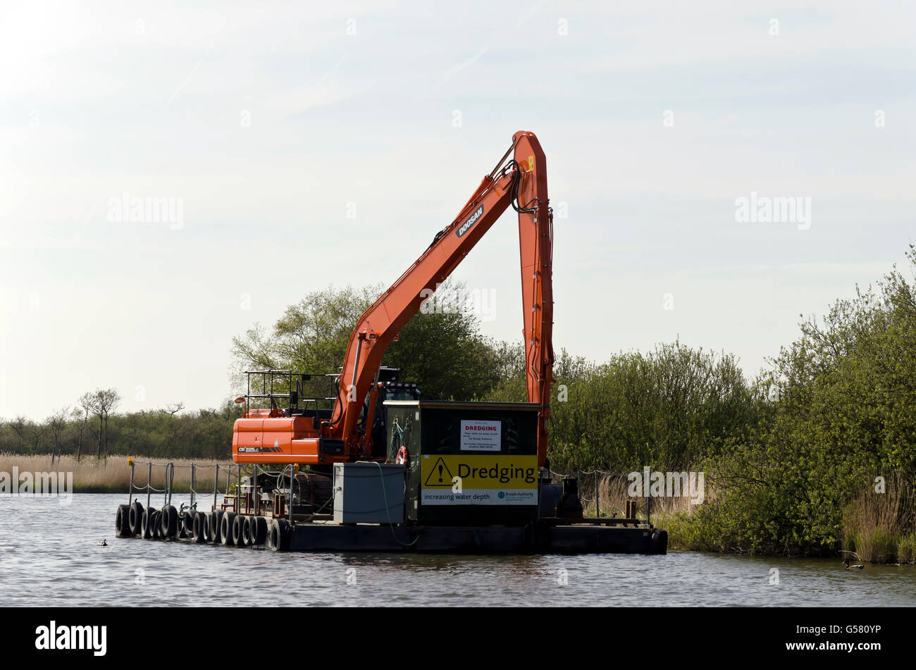 Dredging barge carrying a digger moored on the River Bure in the ...