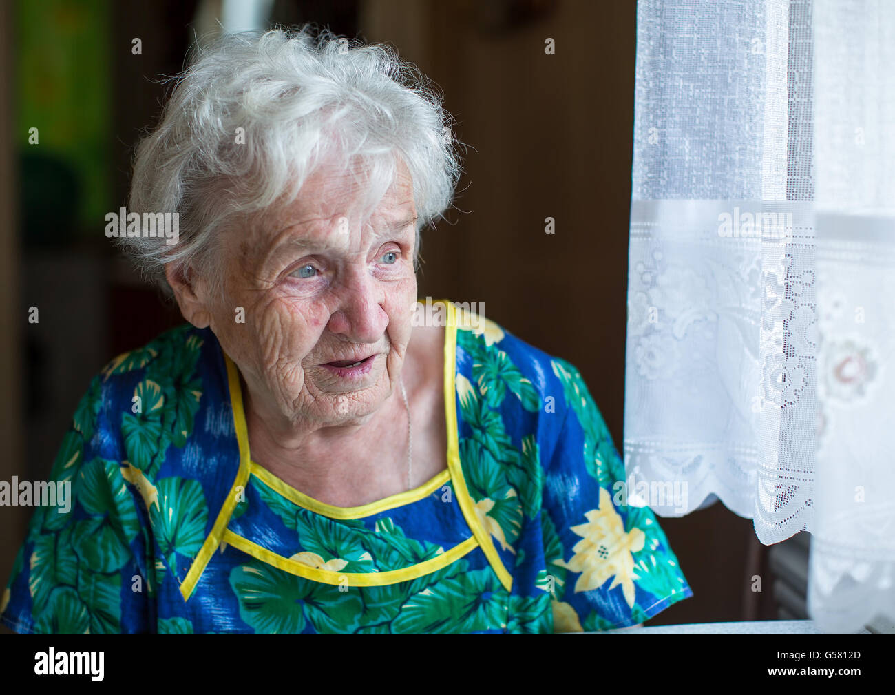 An elderly woman sitting near the window Stock Photo - Alamy