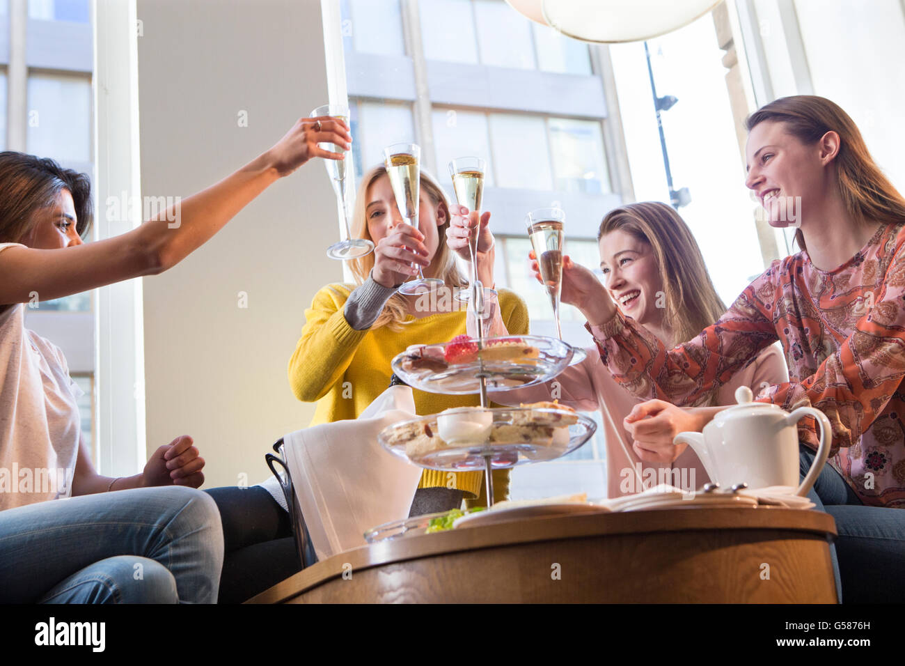Four women toasting champagne over afternoon tea in a cafe Stock Photo ...