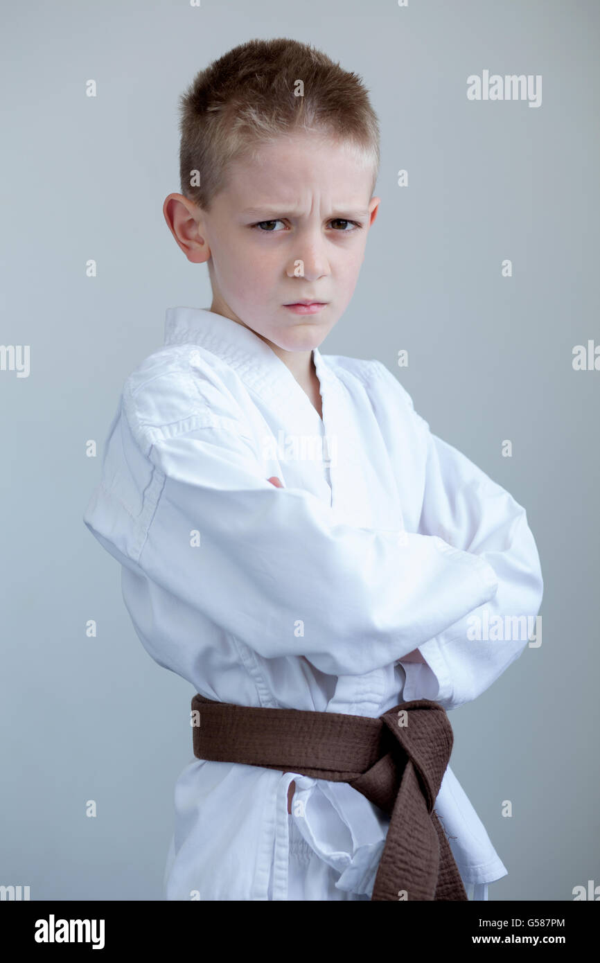 Young boy in karate clothing, posing with a tough expression on his ...