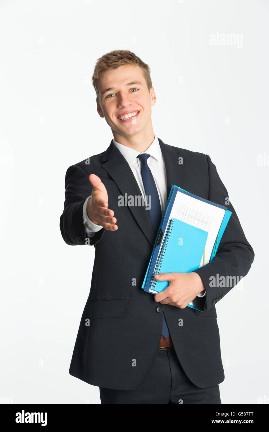 Young businessman holding his hand out to offer a handshake. He is ...