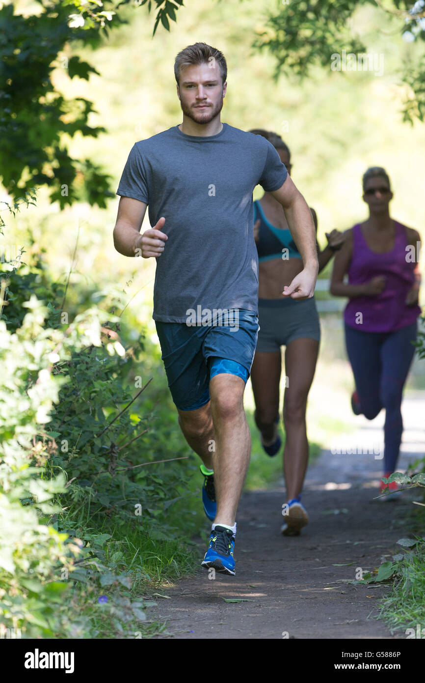 Three people of different ages running along a woodland path Stock ...