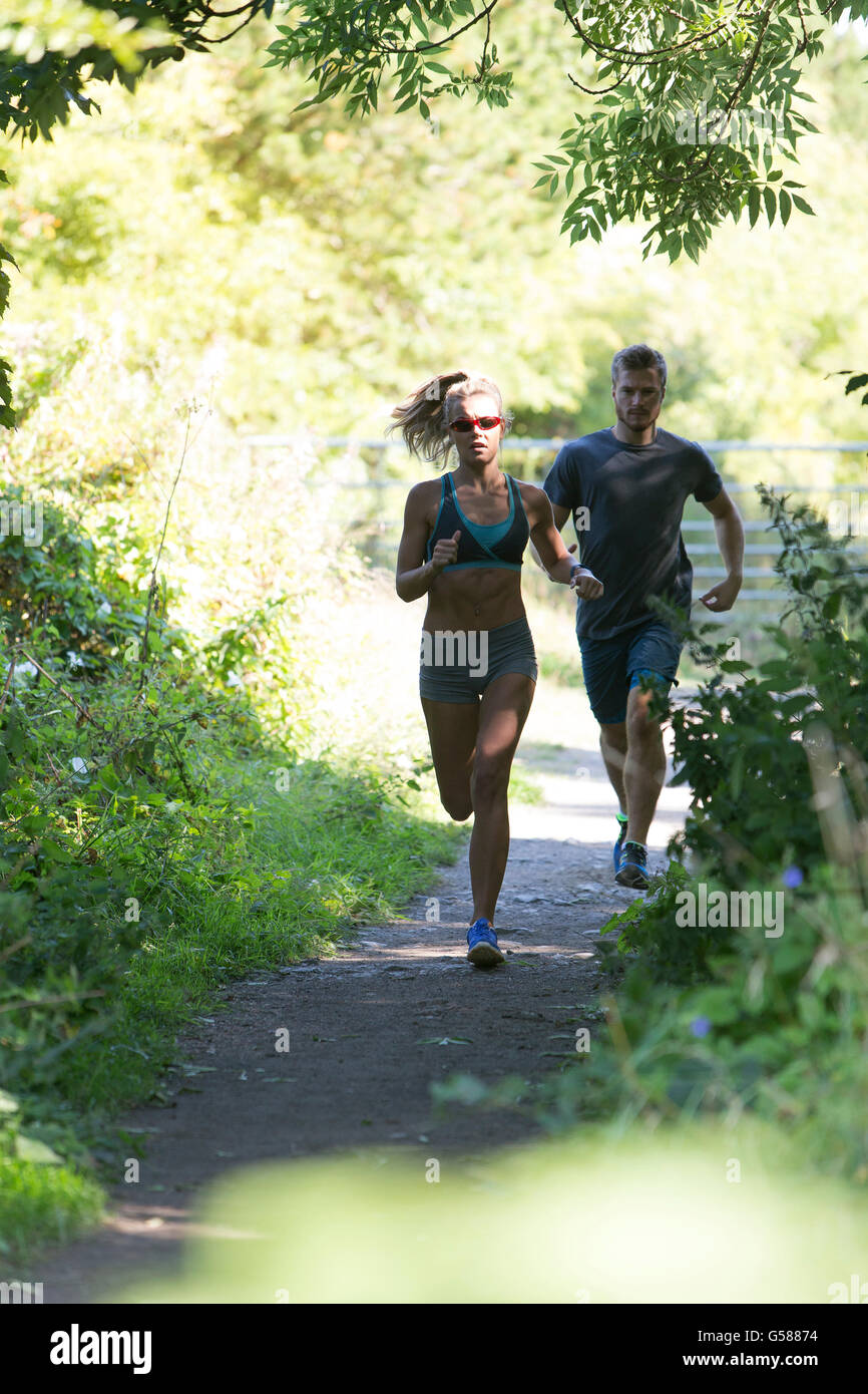 Young couple running along a woodland path together Stock Photo - Alamy
