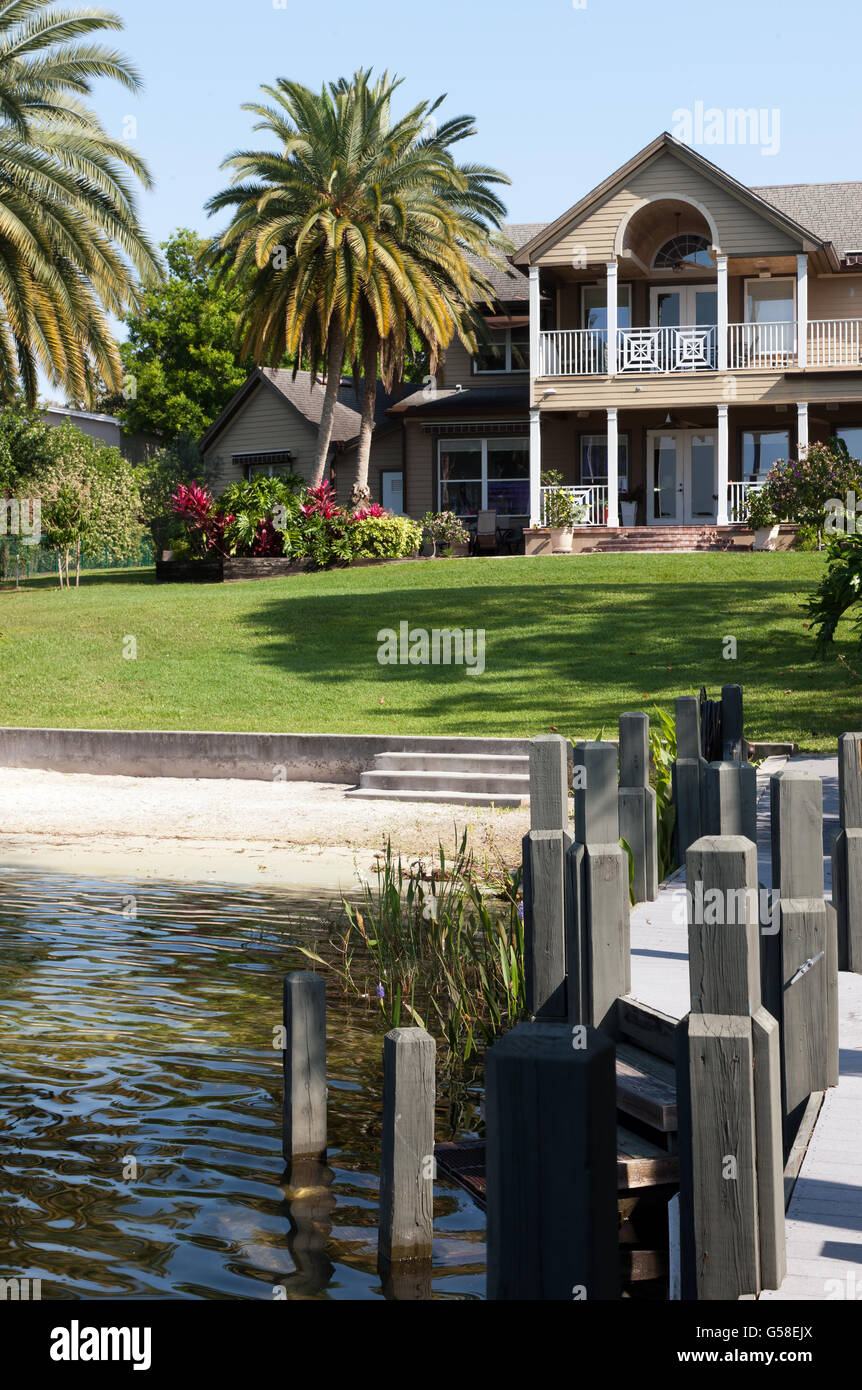 View looking down a private jetty towards a lake-side detached mansion ...