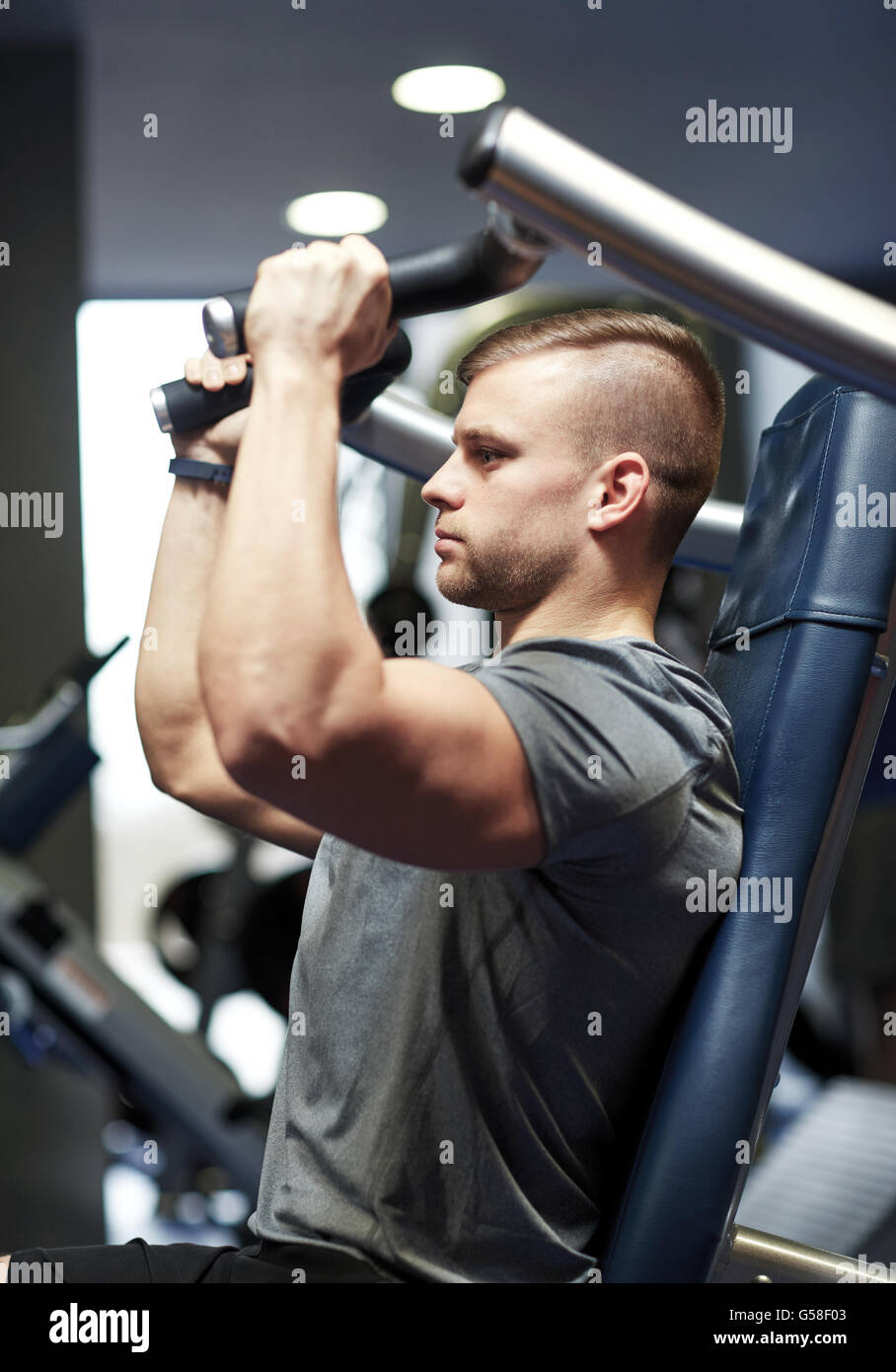 man exercising and flexing muscles on gym machine Stock Photo - Alamy