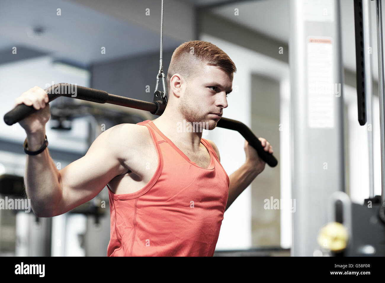 man flexing muscles on cable machine gym Stock Photo - Alamy