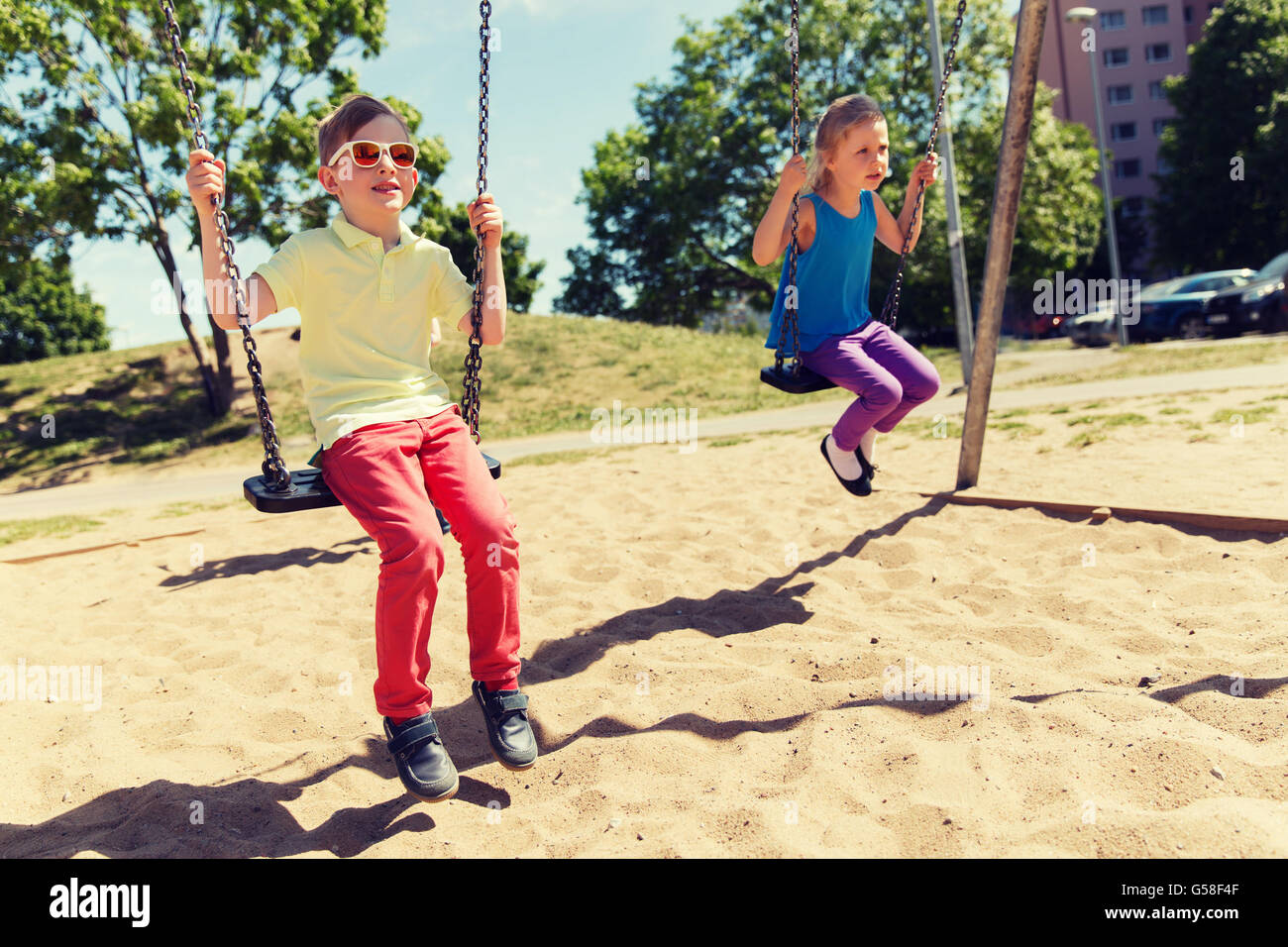 two happy kids swinging on swing at playground Stock Photo - Alamy