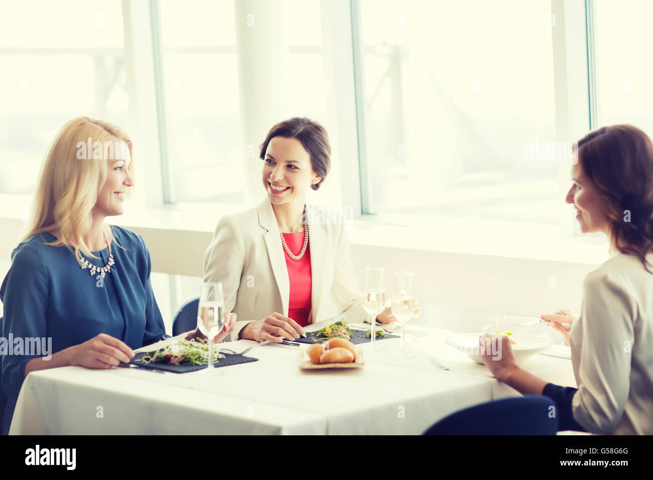 happy women eating and talking at restaurant Stock Photo - Alamy
