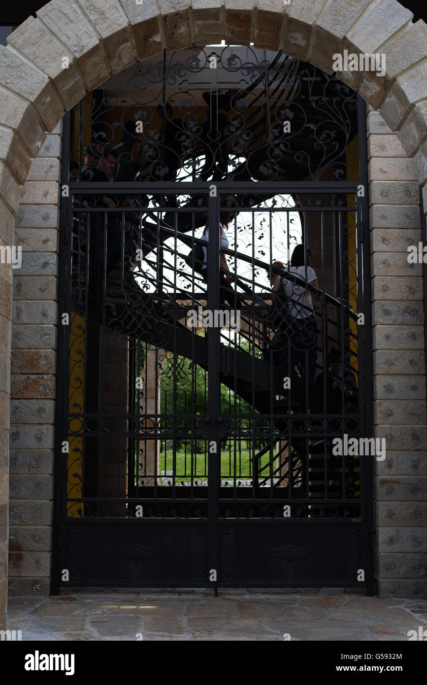 Entrance gate to a high bell tower. Staircase with metal railing behind ...