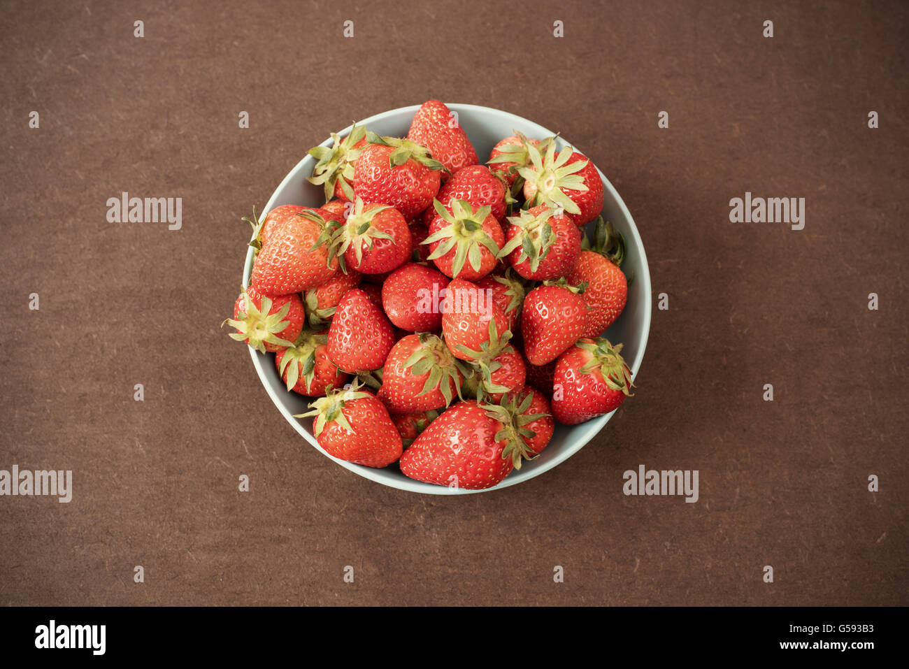 Pile of juicy ripe organic fresh strawberries in a large blue bowl ...