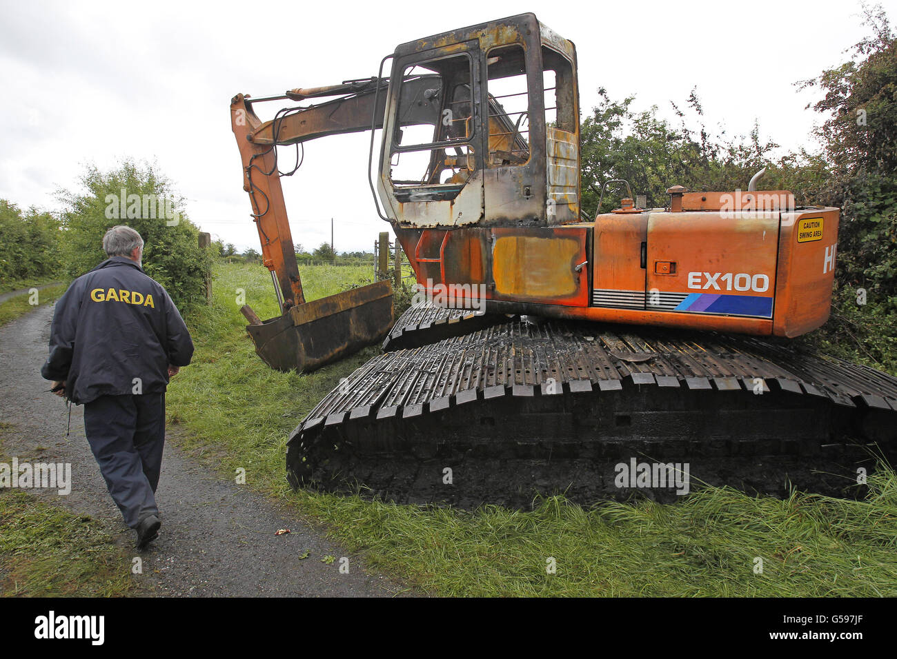 A garda walks past a fire damaged tracked machine at Clonmoylan Bog ...