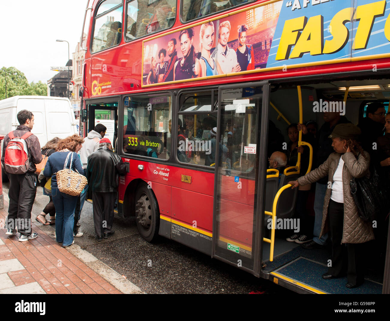 People boarding a bus at a bus stop in south London, as industrial ...