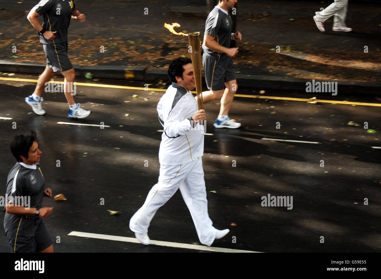 Torchbearer 002 Adam Guest carries the Olympic Flame on the Torch Relay ...