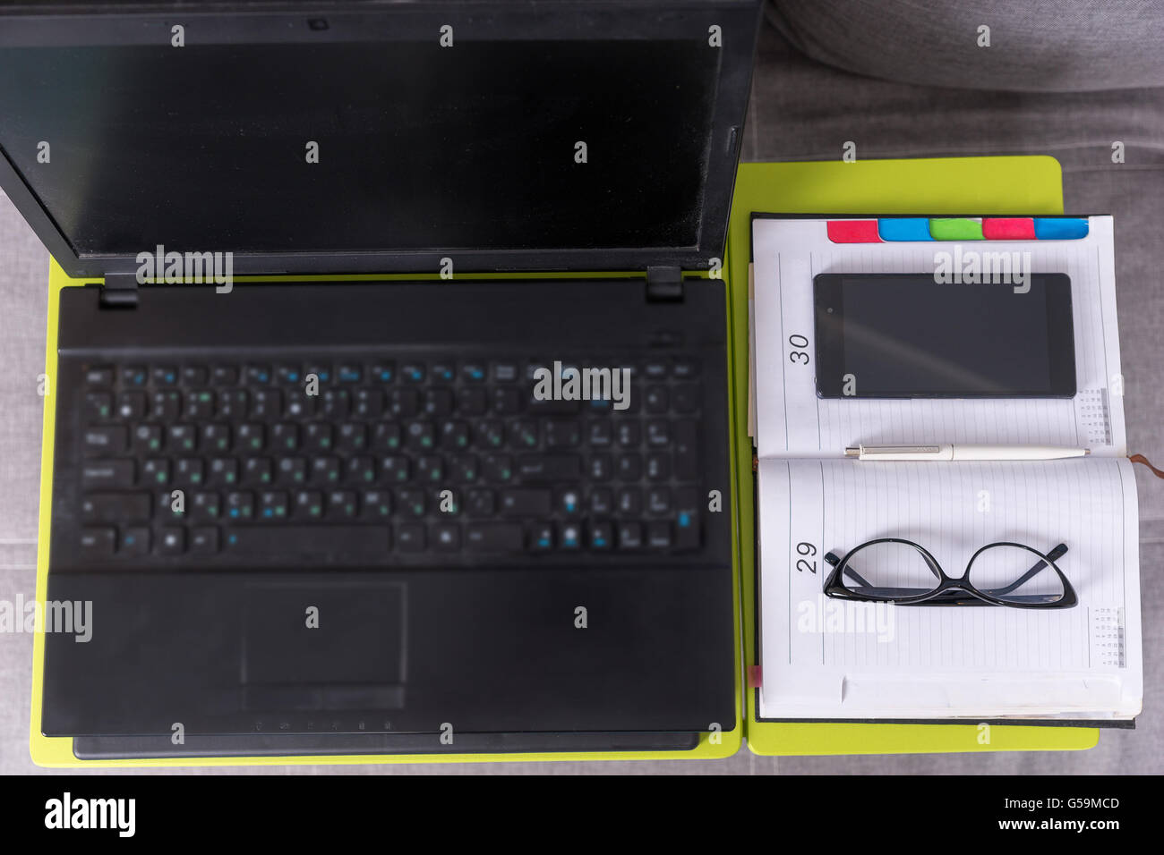 Top view of a tabletop workstation with open laptop, a diary, glasses ...