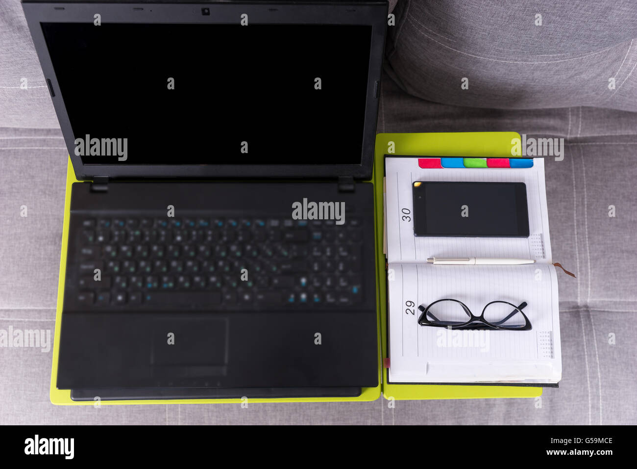 View from above of a tabletop workstation with open laptop, a diary ...