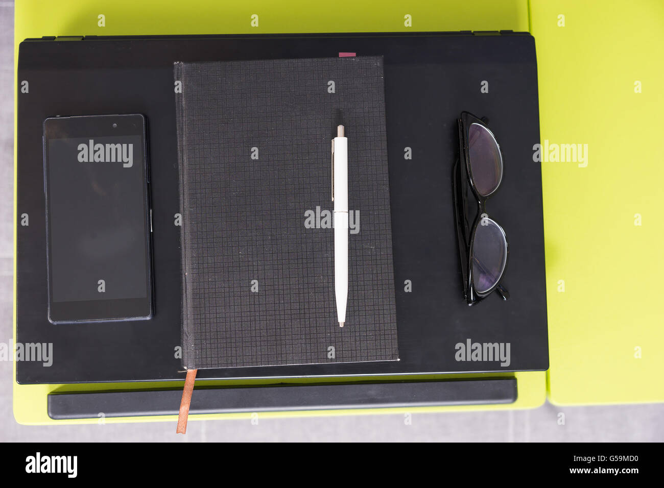 View from above of a tabletop workstation with closed laptop, a diary ...