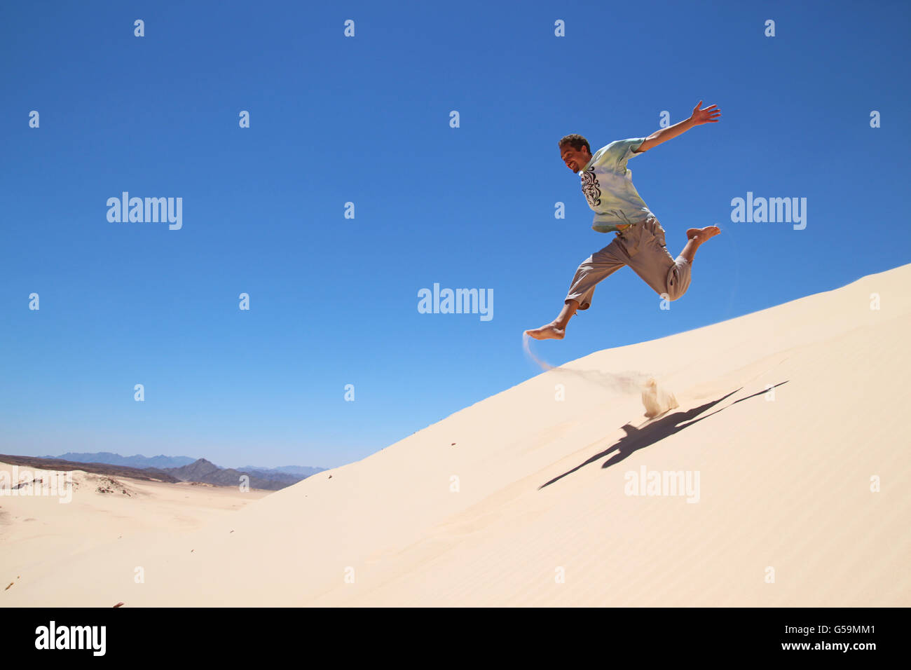 Man in jump on dune slope Stock Photo - Alamy
