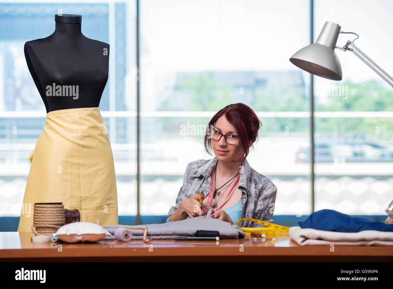 Woman tailor working at her desk Stock Photo - Alamy