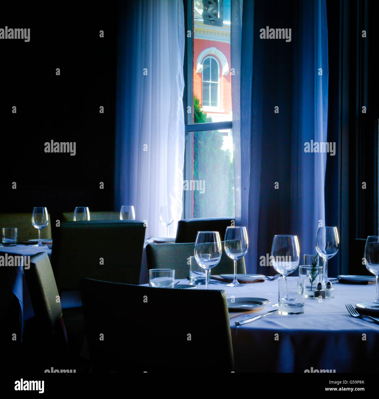 A low light interior of elegant tables with linen tablecloths in a ...