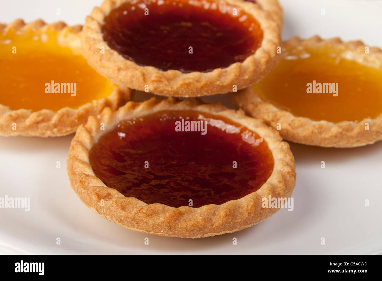 Close up shot of freshly baked assorted jam tarts stacked on a white ...