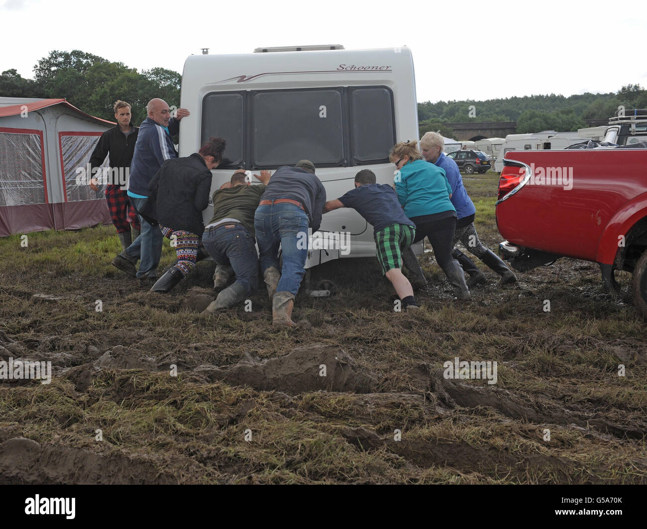 People struggle to move a caravan in stuck in the mud in a campsite at ...