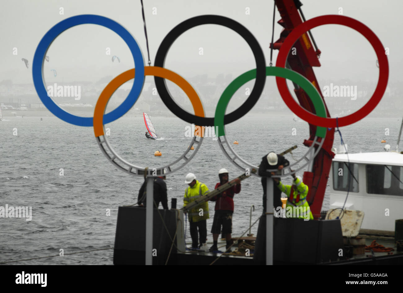 A windsurfer trains in the background as engineers install Olympic ...