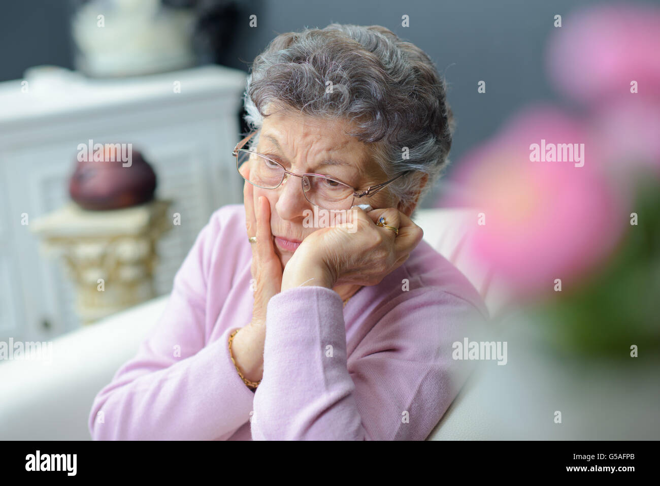 Forlorn elderly lady sitting alone Stock Photo - Alamy
