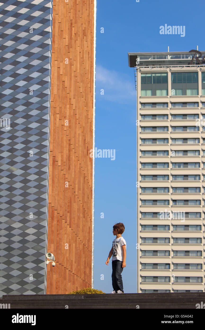 Little boy in the city. Toddler is walking between high-rise building ...