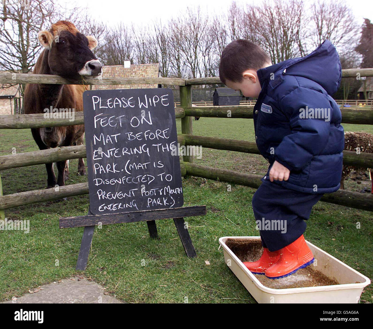 Four year old Jamie Bruce disinfects his boots before attending Treetop ...