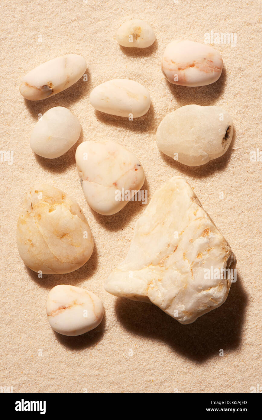 Collection of ten white toned sea stones on sand. Summer beach ...