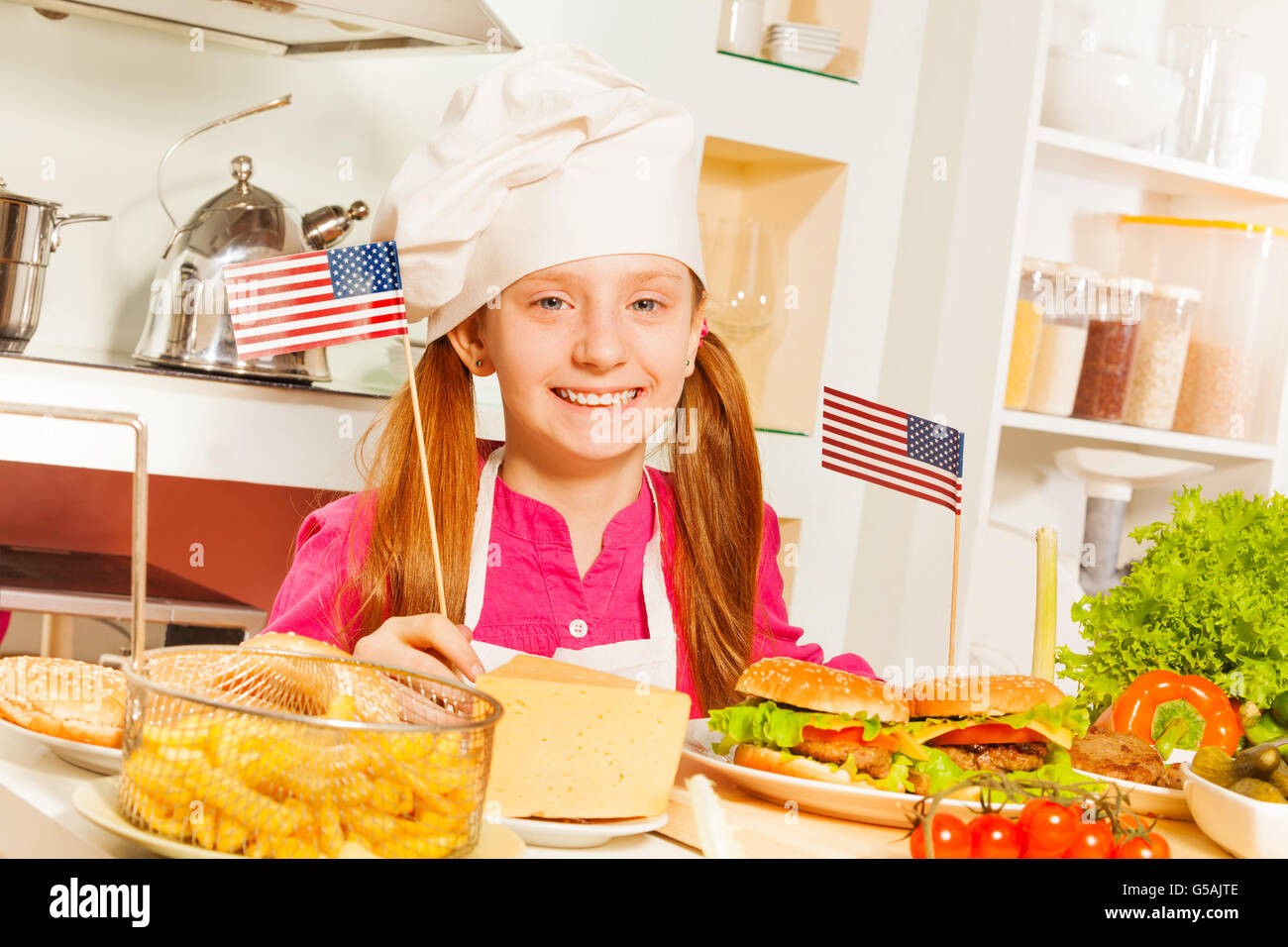 Happy girl in cook uniform preparing American food Stock Photo - Alamy