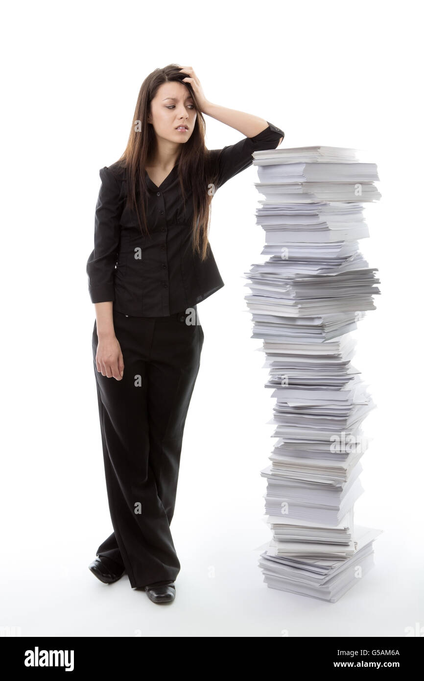 business woman standing against a large pile of paper work not looking ...