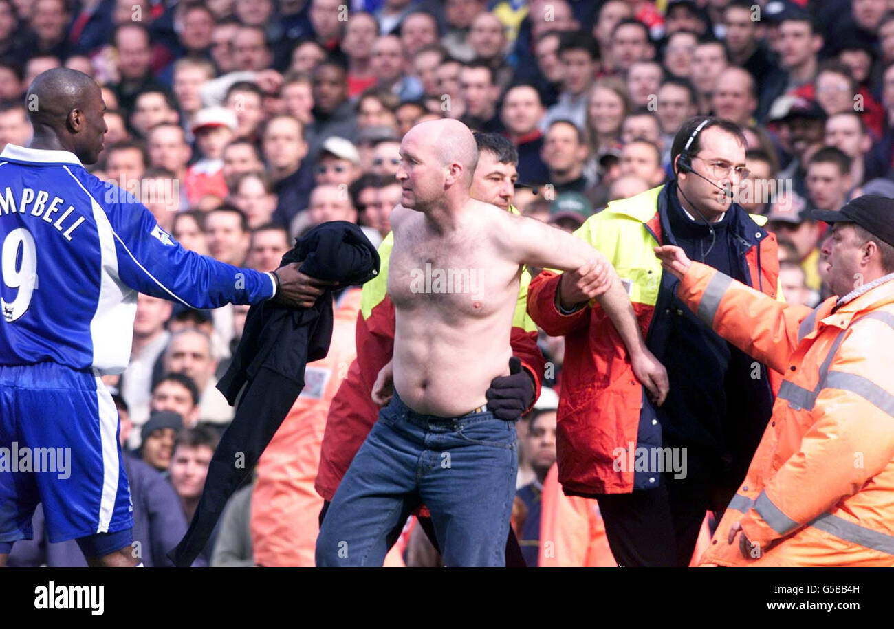 A fan is held back after pulling the shirt of Everton's Alex Nyarko ...