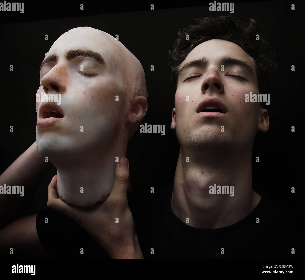 A performer, Charlie Warner, holds a cast of his own head to promote ...