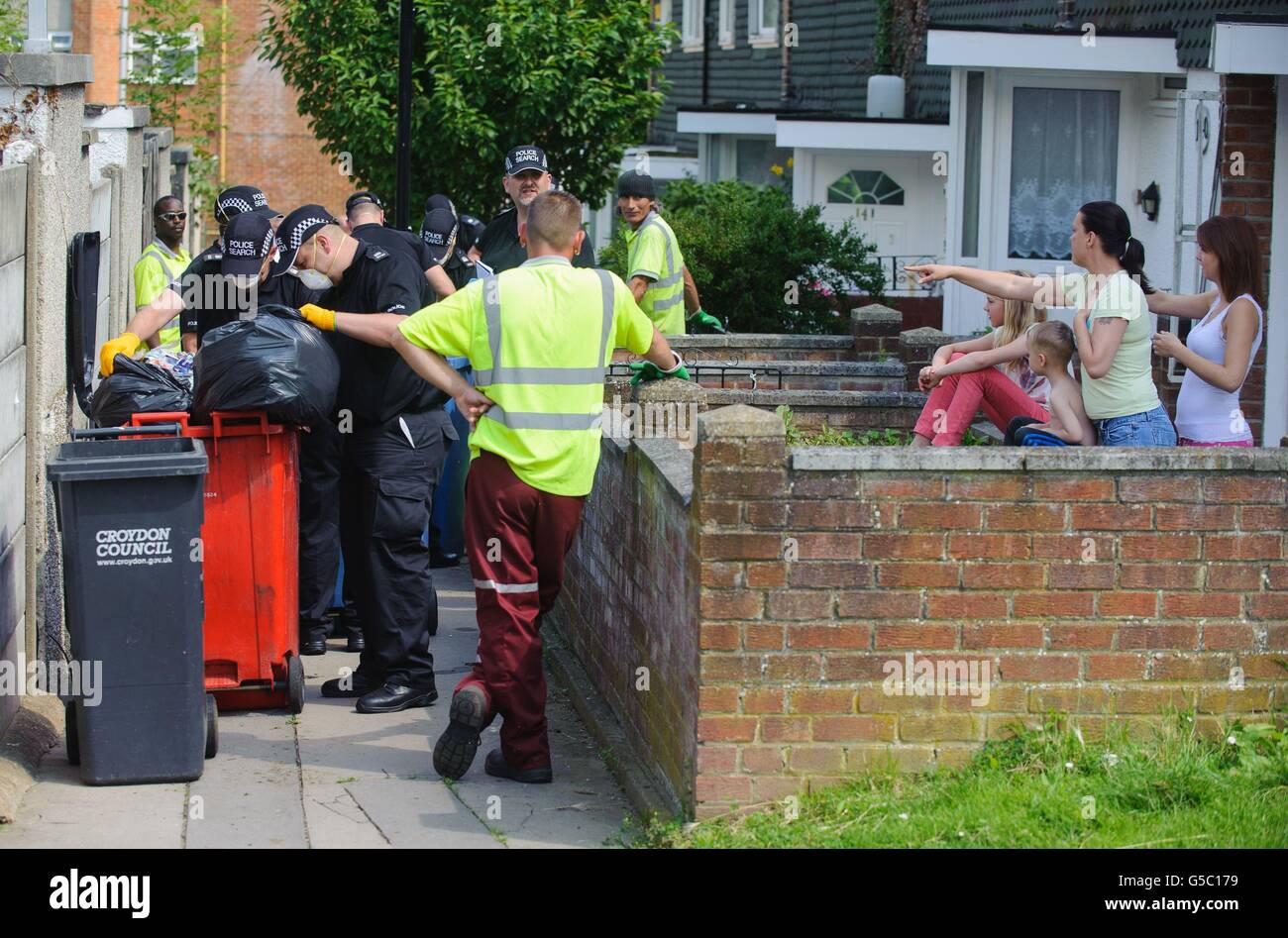 Residents watch as police officers search through rubbish bins near Tia ...