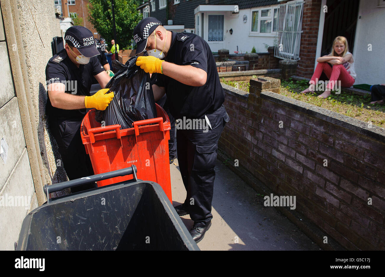 Residents watch as police officers search through rubbish bins near Tia ...