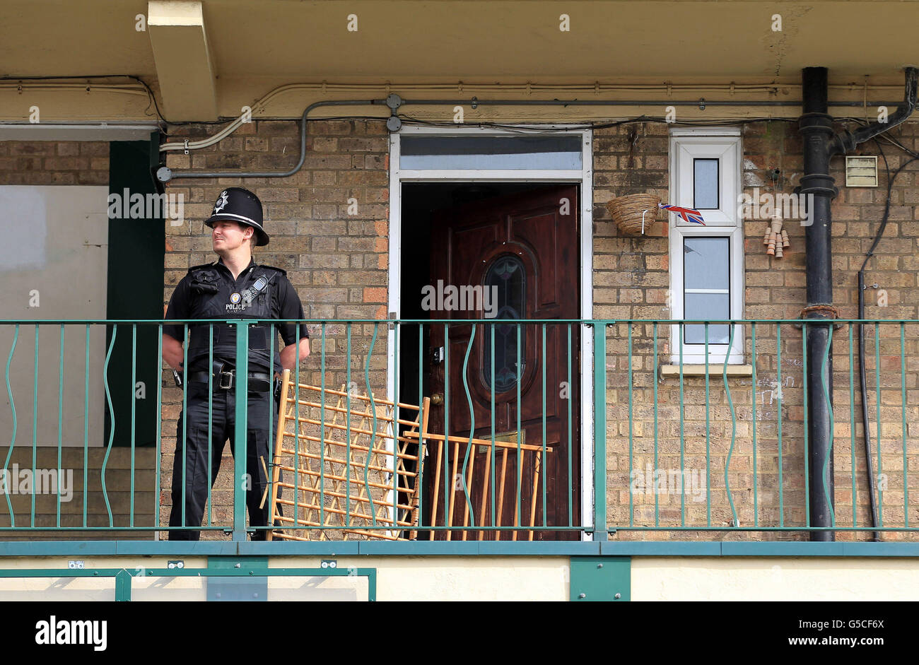 A police officer stands outside a flat in the block, in Mitcham, south ...
