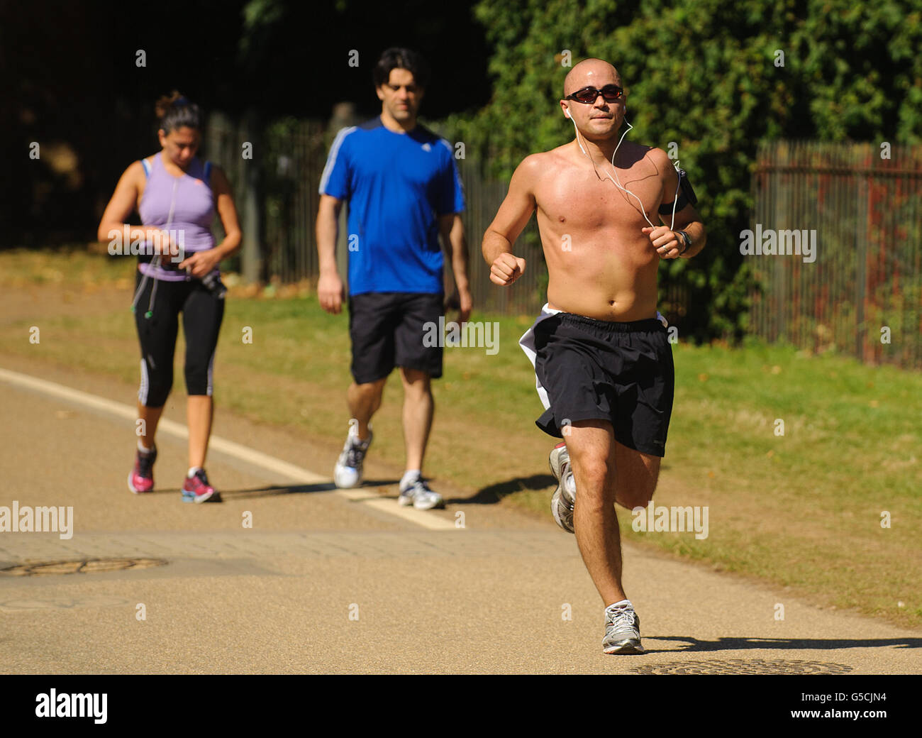 A man goes jogging in the sunshine in Hyde Park, central London as ...