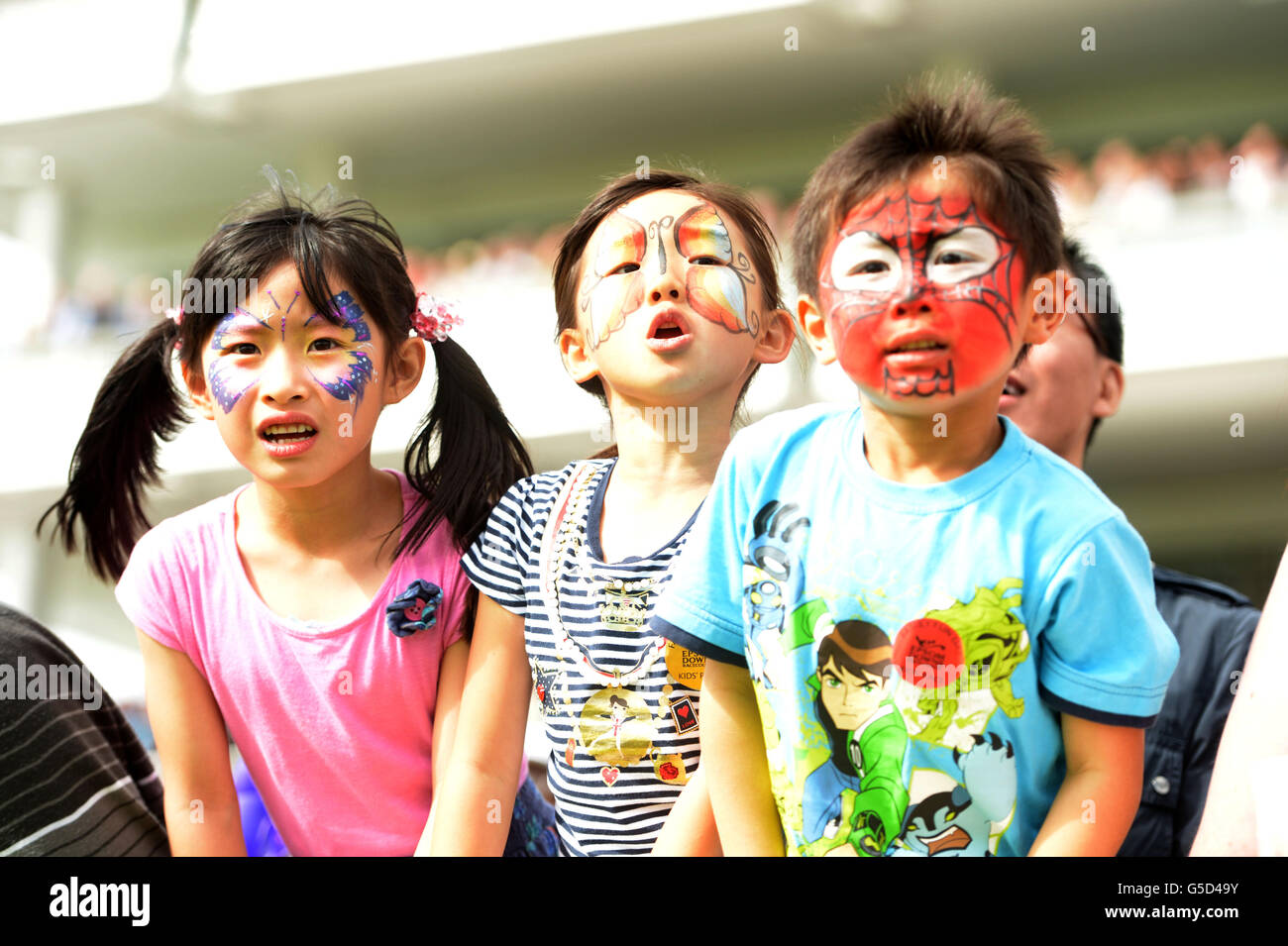 Kids with painted face watch the early races at Epsom Stock Photo - Alamy