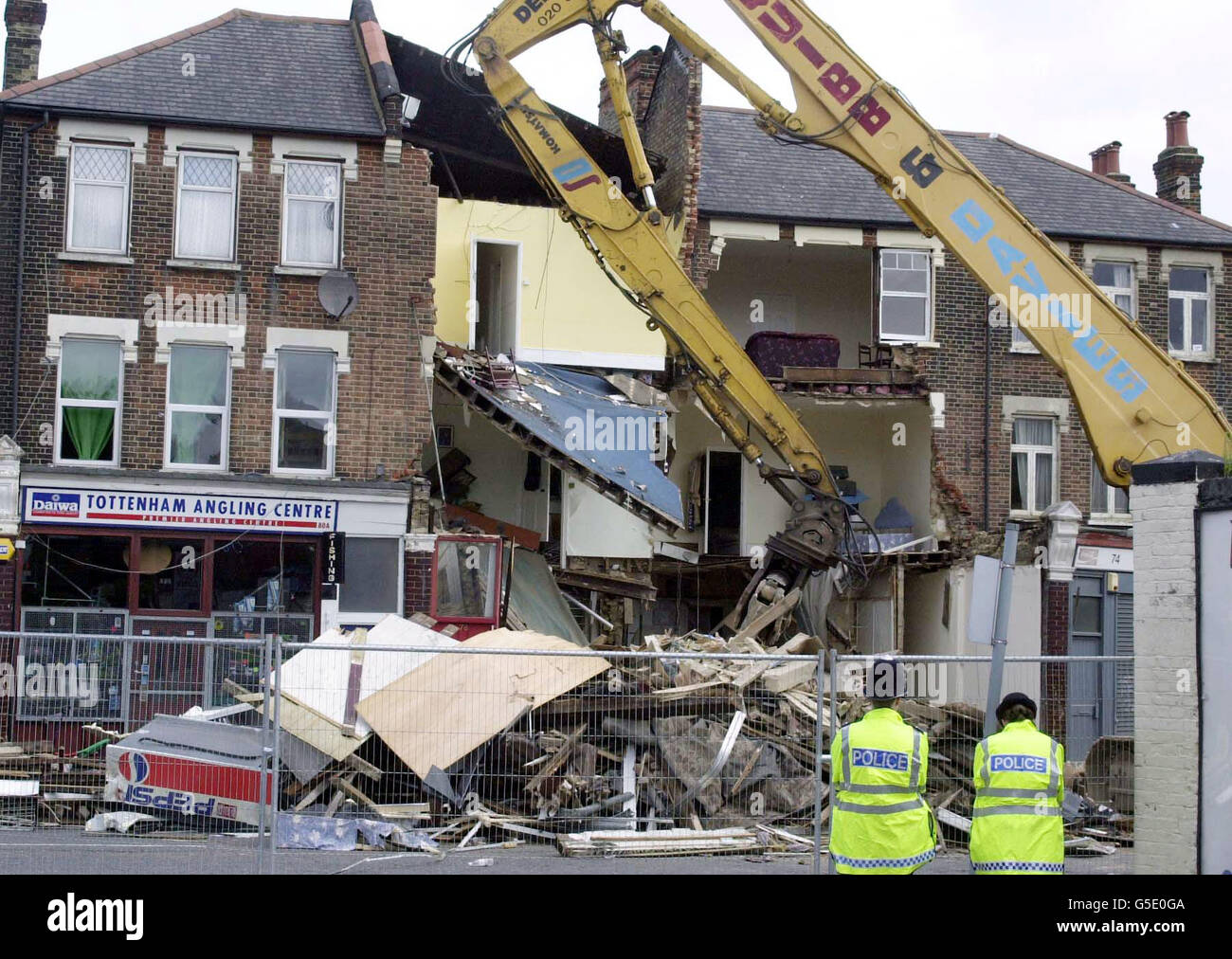 A mechanical digger help clear rubble from the collapsed three-storey ...