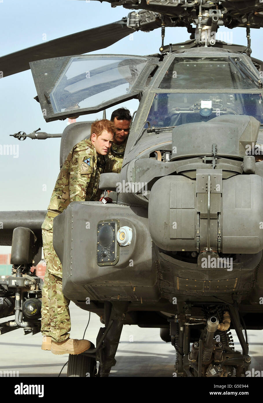 Prince Harry examines the 30mm cannon of an Apache helicopter with a ...
