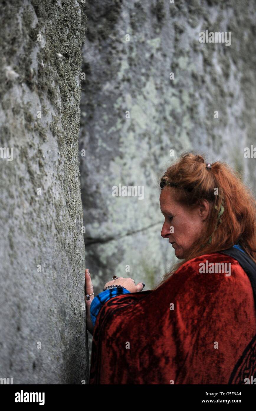 A member of the public touches one of the main stones at Stonehenge in ...