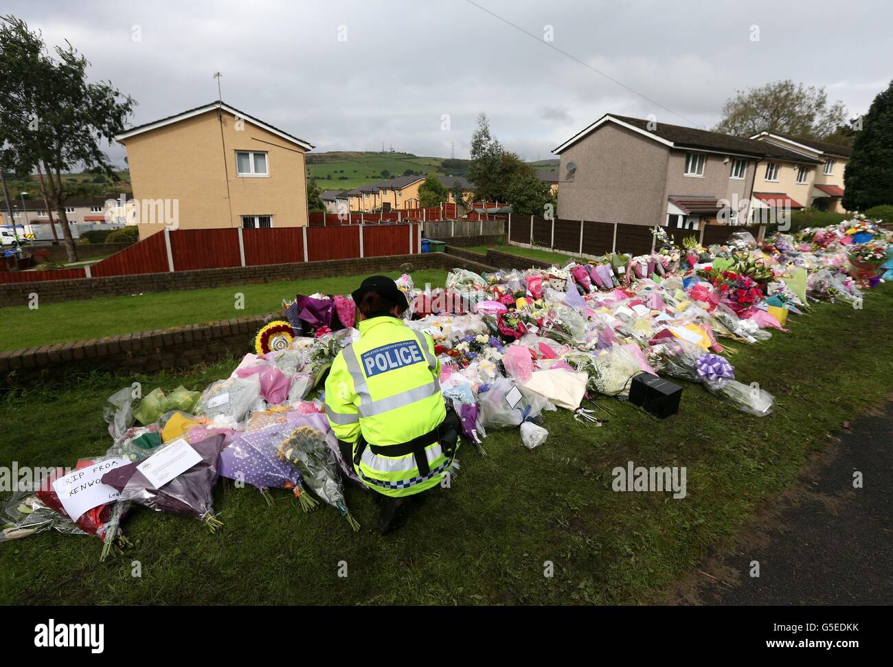 A police officer looks at flowers left at the scene of the shooting of ...