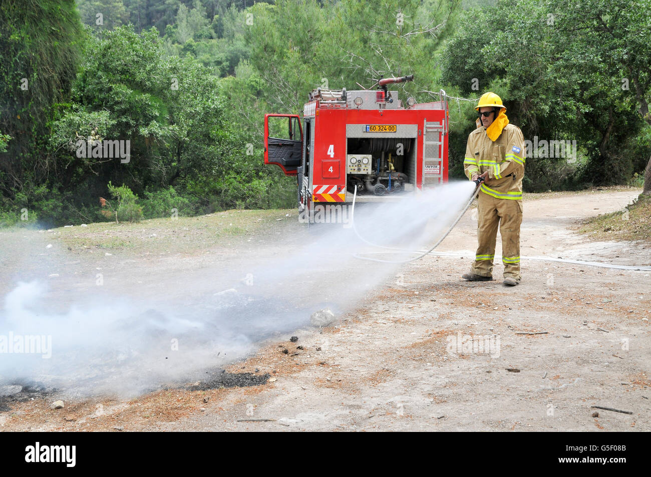 Fireman in protective clothing extinguishes a fire as part of a fire ...