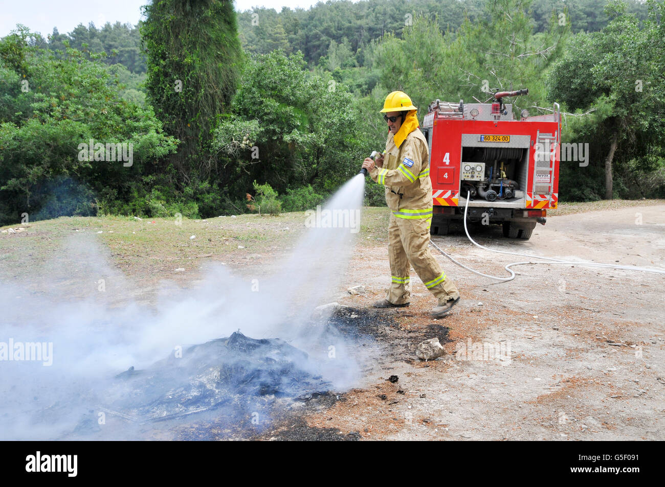 Fireman in protective clothing extinguishes a fire as part of a fire ...